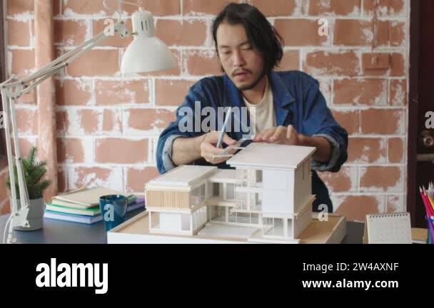 Smart asian male Architect working with his architectural model ...