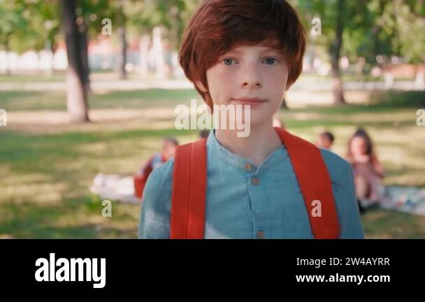 Tracking portrait shot of cute schoolboy with red hair and freckles ...