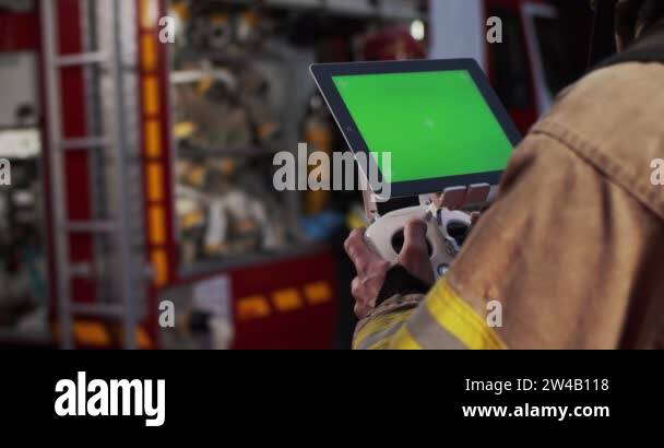 Portrait of firefighter controling drone, looking at scale of fire ...