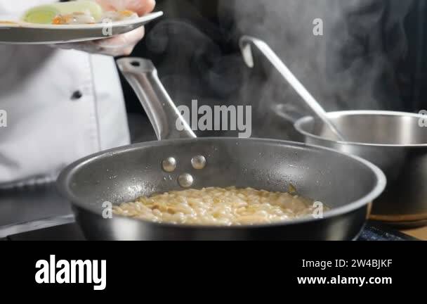 Cooking delicious seafood risotto in frying pan. Shot in slow motion ...