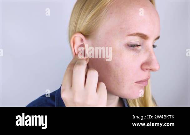 A woman on a white background shows her ear. The macro video shows the ...