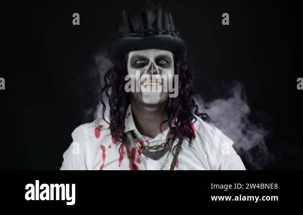 Scary guy in costume of Halloween skeleton in bloody shirt, listening ...