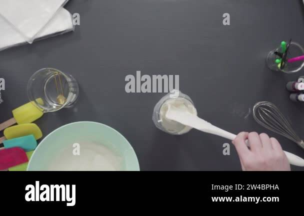 Step by step. Flat lay. Mixing in food coloring into the royal icing to ...