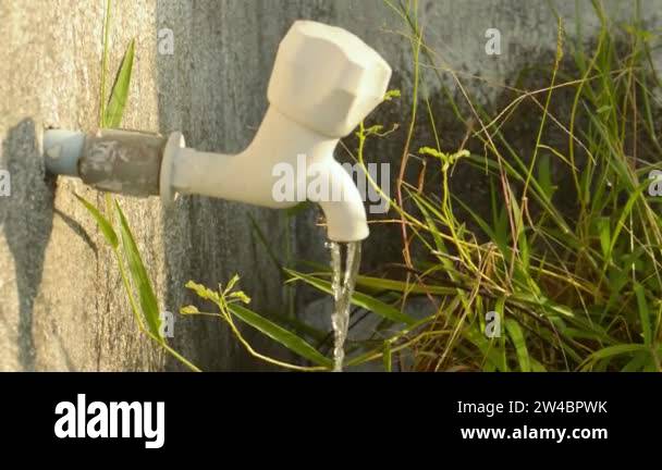 Drop of water falling from an open tap in the back yard garden of a ...