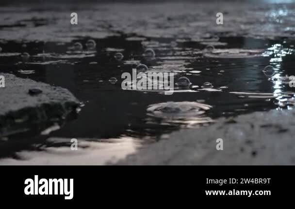 autumn rain, puddle on road. Drops of rain water fall into large puddle ...