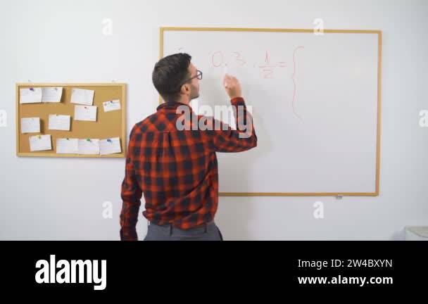 Young male math teacher writing mathematical equations on whiteboard ...
