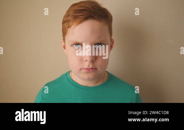 Portrait of little serious red-haired boy with freckles indoor. Unhappy ...