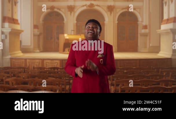 Cheerful african american gospel singer standing at row of wooden ...