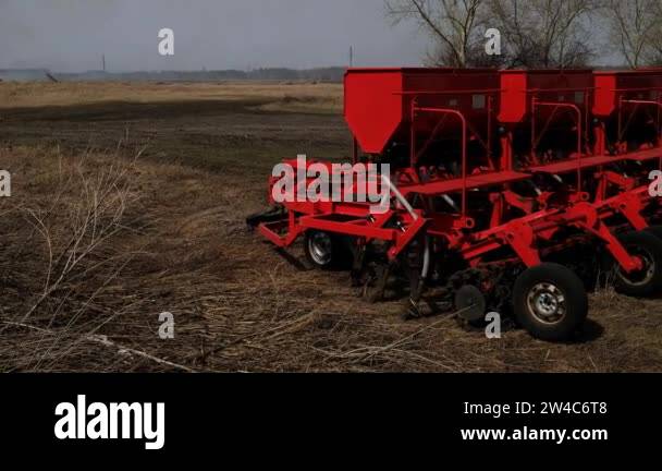 Modern sowing seeds machine. Farmer tractor seeding. Red combine plow ...