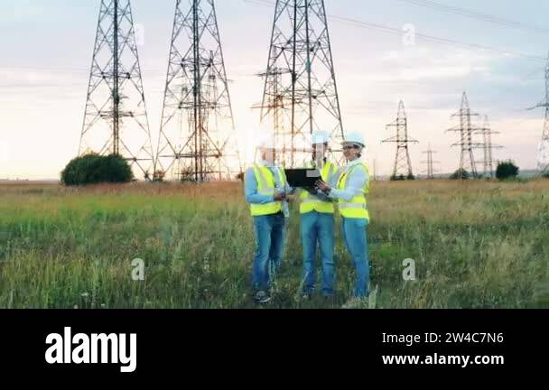 Field with transmission towers and a group of engineers. Energy saving ...