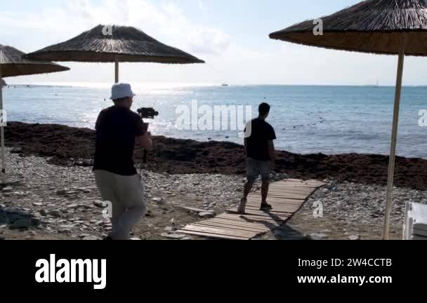 Videographer taking pictures and video of the ocean views and a man ...