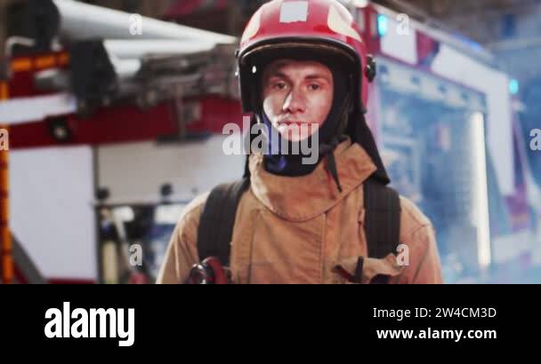 Portrait of firefighter approaches from fire van with flashing lights ...