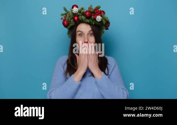 Happy shocked woman in traditional Christmas wreath, keeps palm on ...