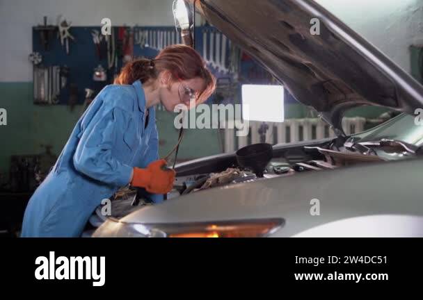 A beautiful female mechanic empowering working on a car in a car ...