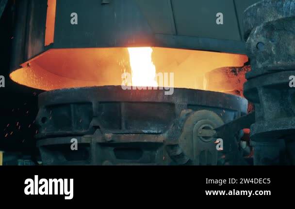 Molten metal is pouring into a massive container. Metallurgical factory ...