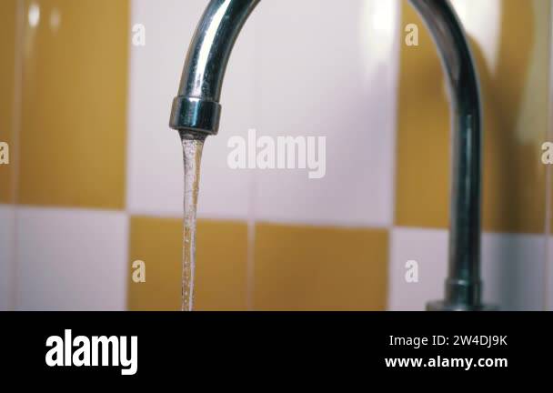 Water is pouring from the tap. Pressure of water jet in the faucet in ...