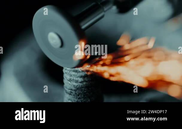 Metal bolt of car engine is grinded with hand-held power tool. Close-up ...