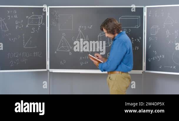 Caucasian male mathematician in glasses at backboard with math or ...