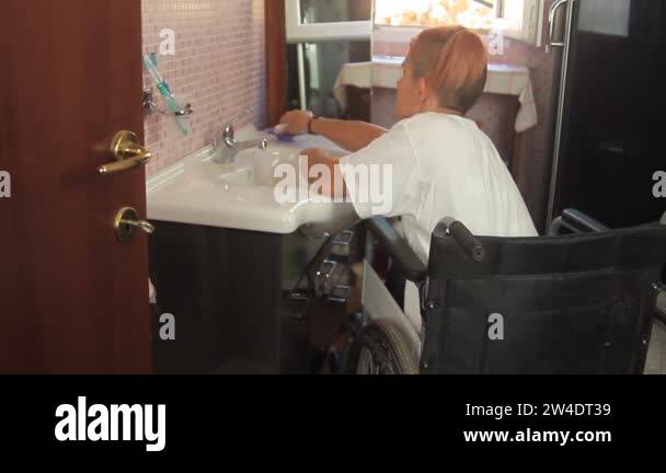 daily life of a disabled person in a wheelchair in the bathroom washing ...