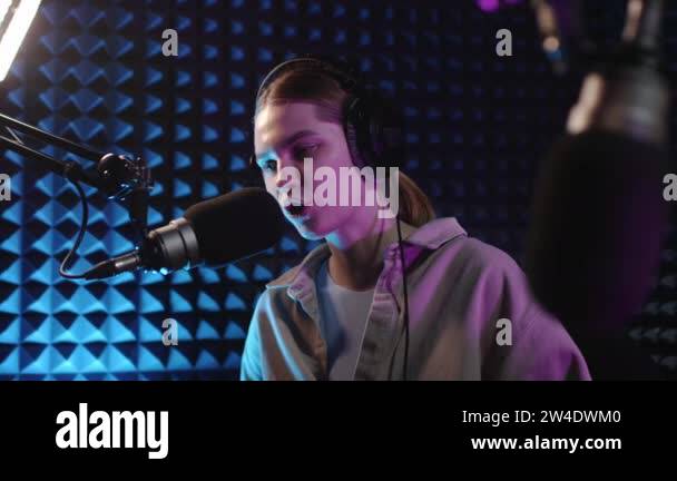 Beautiful young girl dj speaks into microphone, records podcast or ...
