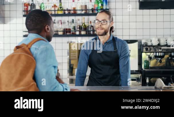 Caucasian male bartender taking order from African American guy tourist ...
