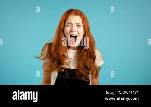Young scared girl shouting loud isolated over blue background. Stressed ...