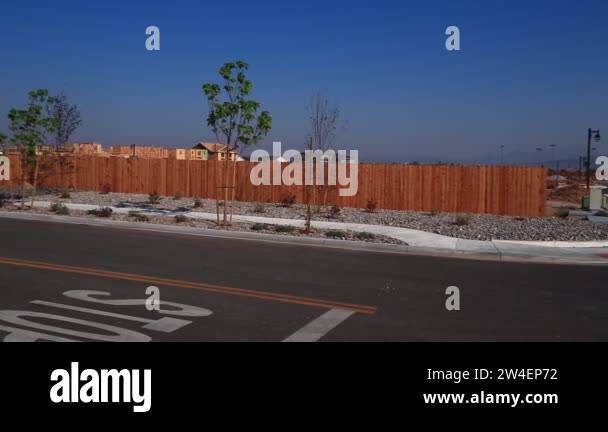 Pan left over newly built street intersection and tree lined fencing ...