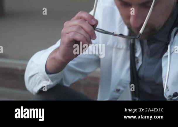 Tense doctor man examines x-ray on stairs outside clinic. Medical ...