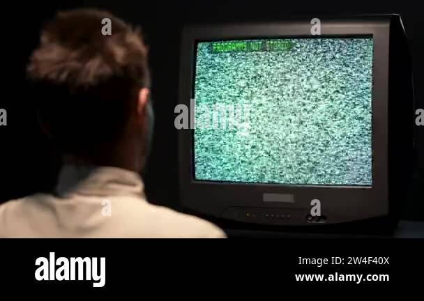 Over the shoulder of a man holding a retro TV remote control and ...