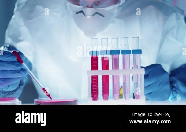 Tilt up shot of male lab scientist in protective uniform drawing red ...