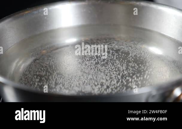 Water boiling in saucepan, Bubbles from boiling water. macro shot of ...