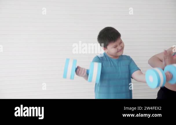 Asian family son fat exercise with dumbbell and mother cheer at home ...