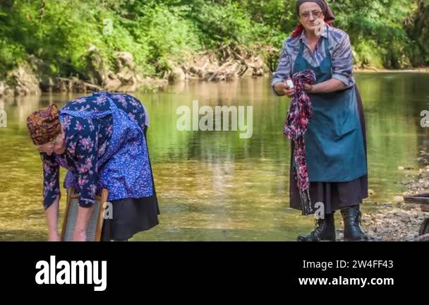Very old ladies are washing clothes in a river on a nice sunny day ...