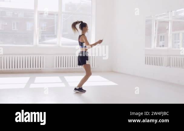 Cute young girl jumping rope in gym and smiling, warm up before ...