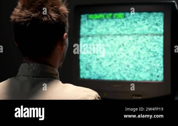 Over the shoulder of a man holding a retro TV remote control and ...