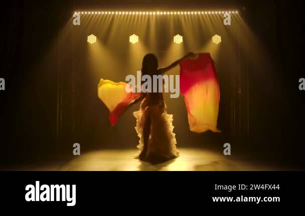 Belly dancer dancing with silk fan tissues. Shot in a dark studio with ...