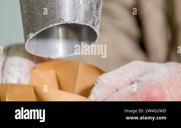 We can see a flour falling into a paper bag when a man opens up the bag ...