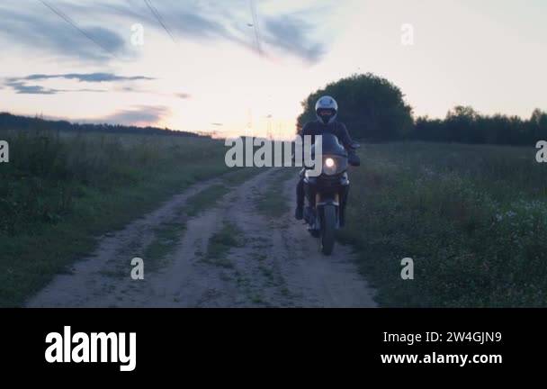 motorcyclist biker rides a motorcycle. Rides on a country road against ...