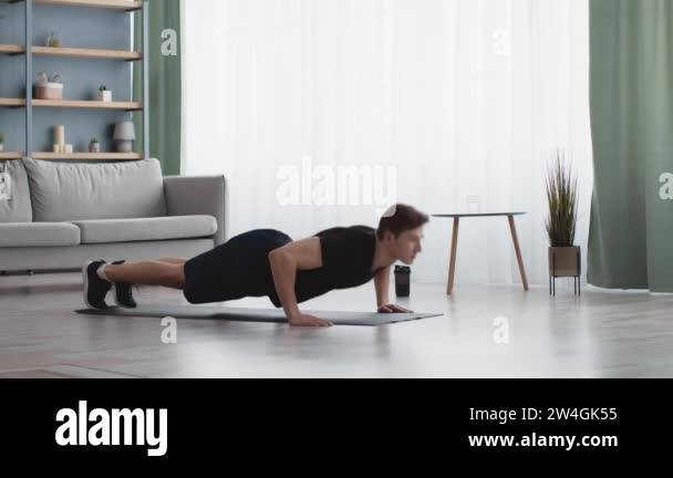 Young strong guy practicing push ups exercise at home, exercising push ...