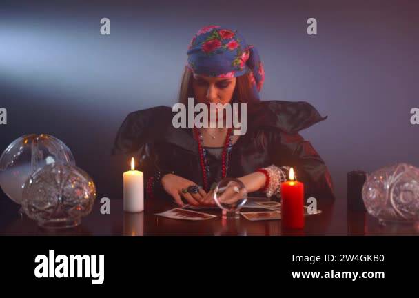 Young powerful female fortune teller spelling over photos using red ...