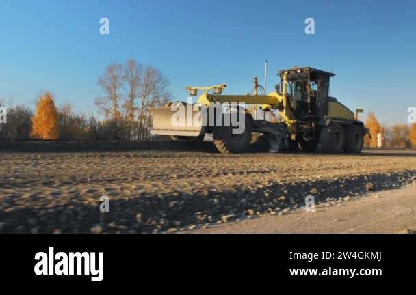A motor grader levels bulk building materials for a new road ...
