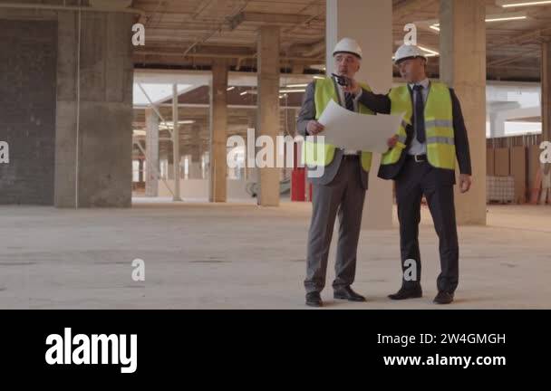 Wide shot of two male Caucasian construction workers wearing formal ...