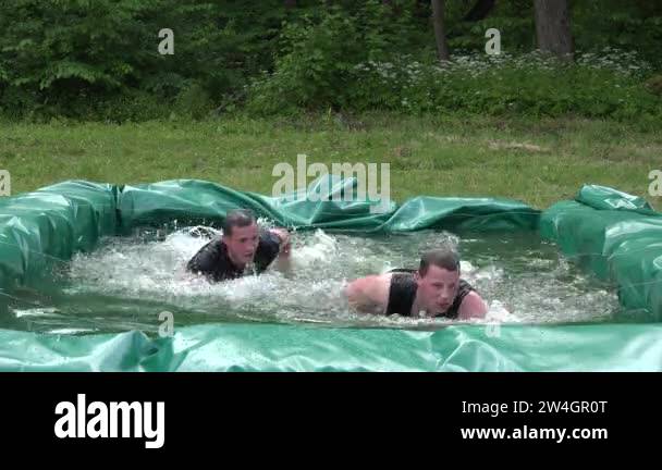 two young men compete diving in small water pool with hurdles. 4K Stock ...