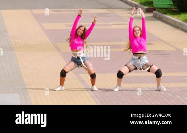 Two cheerful young girls in short shorts dancing dancehall with ...