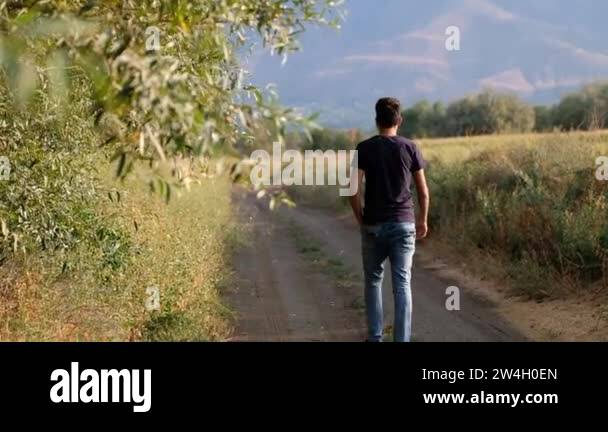 Alone thoughtful man walking in the outdoors with guitar in hand at ...