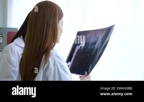 Two women doctors consulting diagnostics using x-ray film at hospital ...
