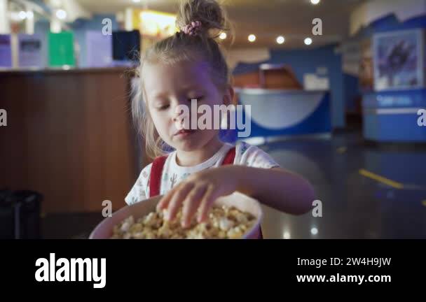 Little girl eating popcorn. Media. Cute girl chewing sweet popcorn at ...