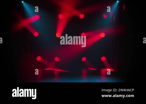 Red moving spotlights and blue beams on an empty stage in the dark ...