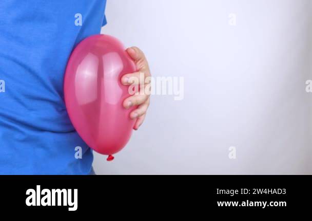 Conceptual video. The man holds a red ball near his belly, which ...