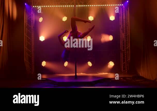 The dancer makes a dance movement on the pylon. A young slender woman ...